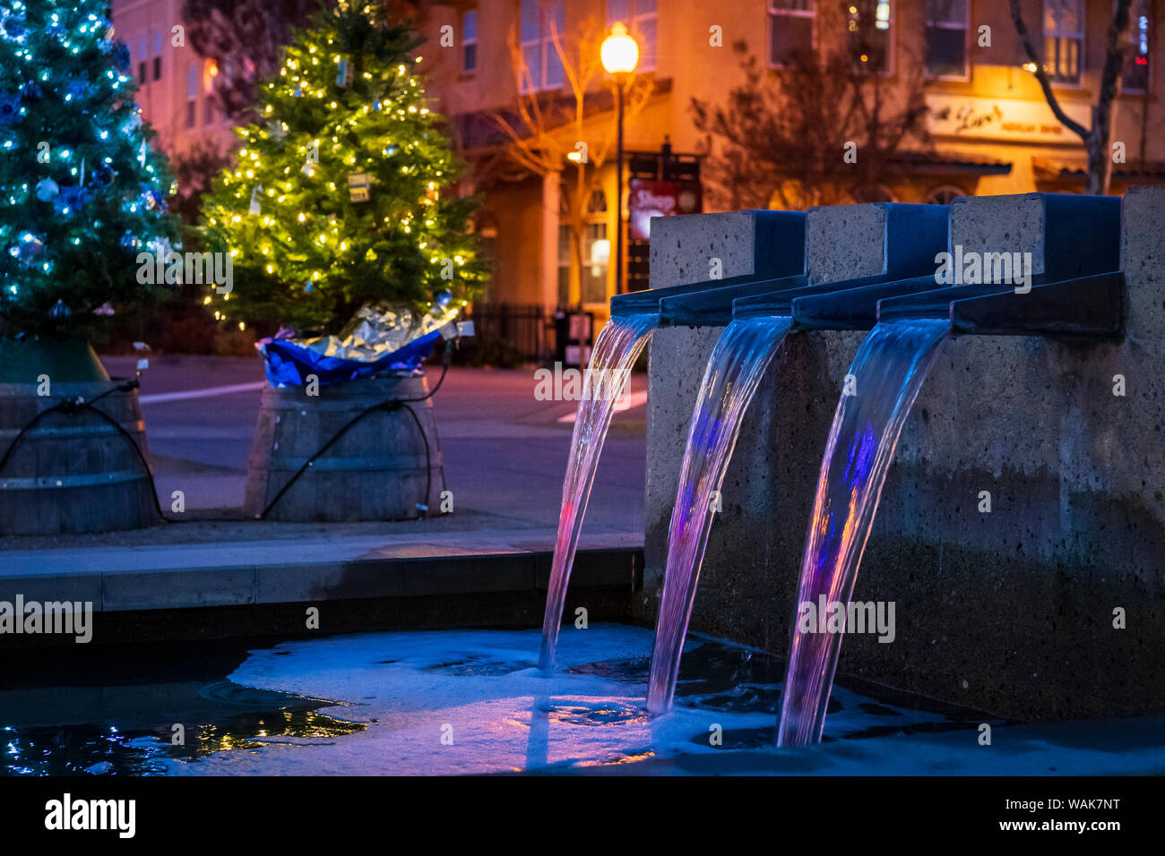 Christmas lights color the waterfall from the fountain in the city ...