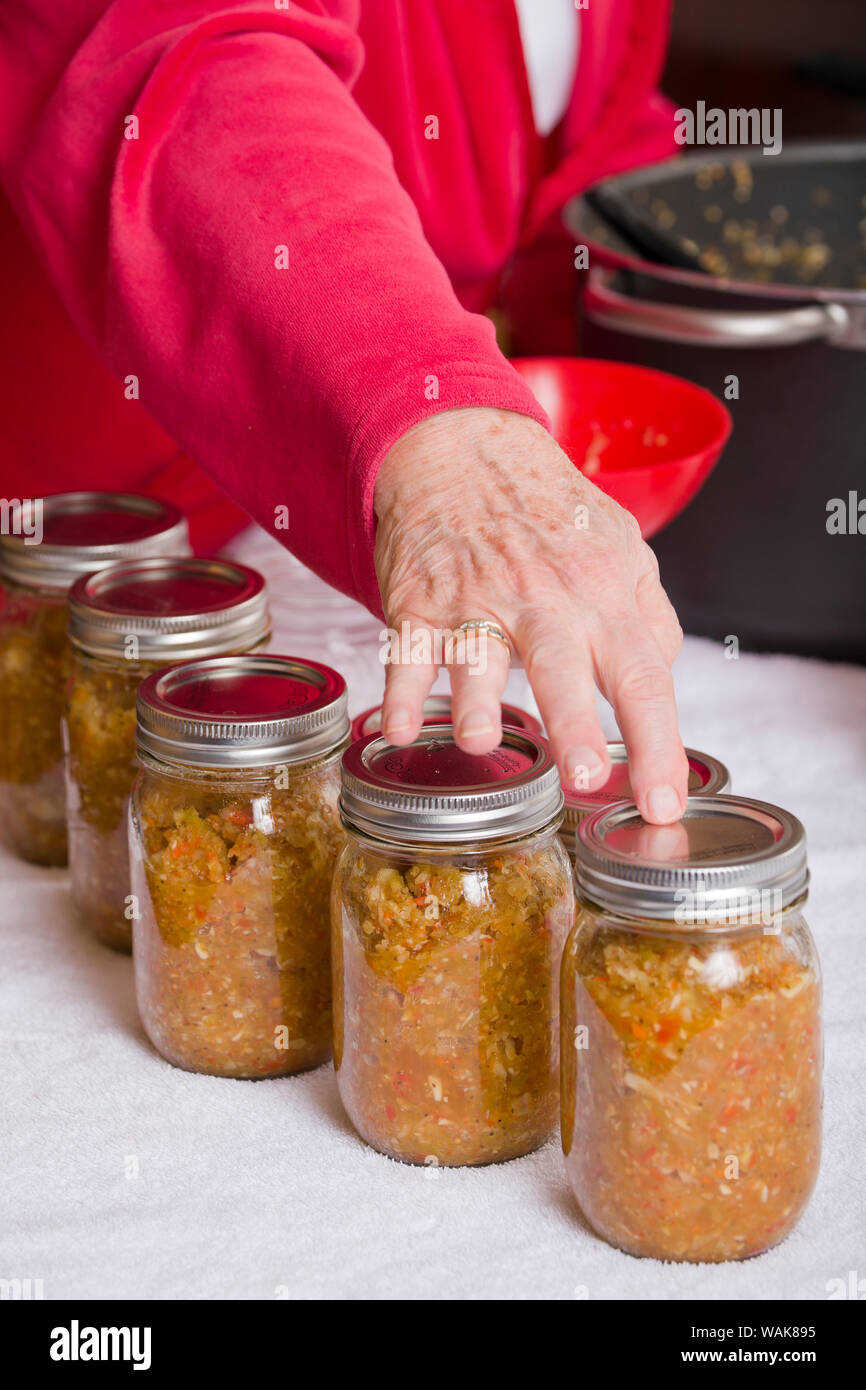Woman checking canning seals on jars of home-canned relish. (MR Stock ...