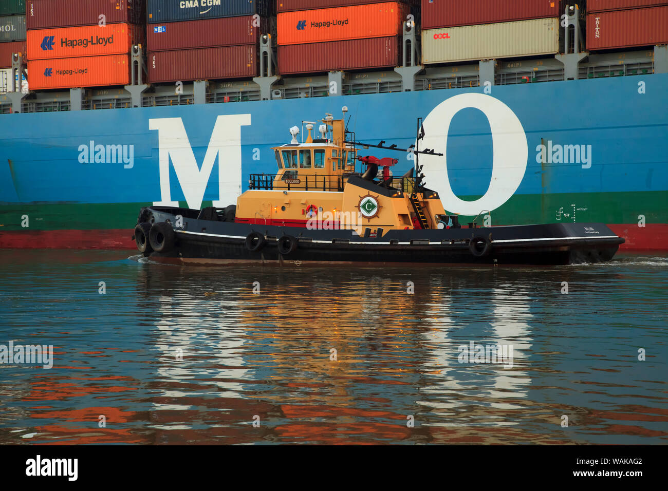 USA, Georgia, Savannah. Cargo ship entering the port, escorted by a tug ...