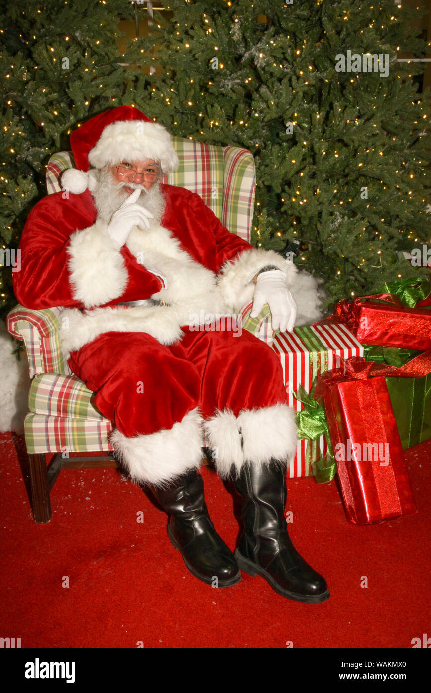 Full length portrait of Santa Claus sitting in a red and green armchair ...