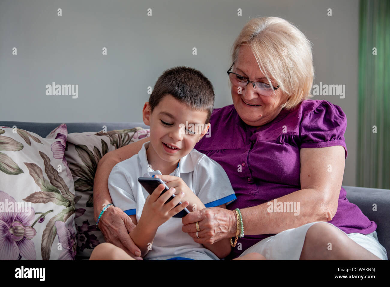 Happy grandmother and cute grandson using cellphone together, smiling ...