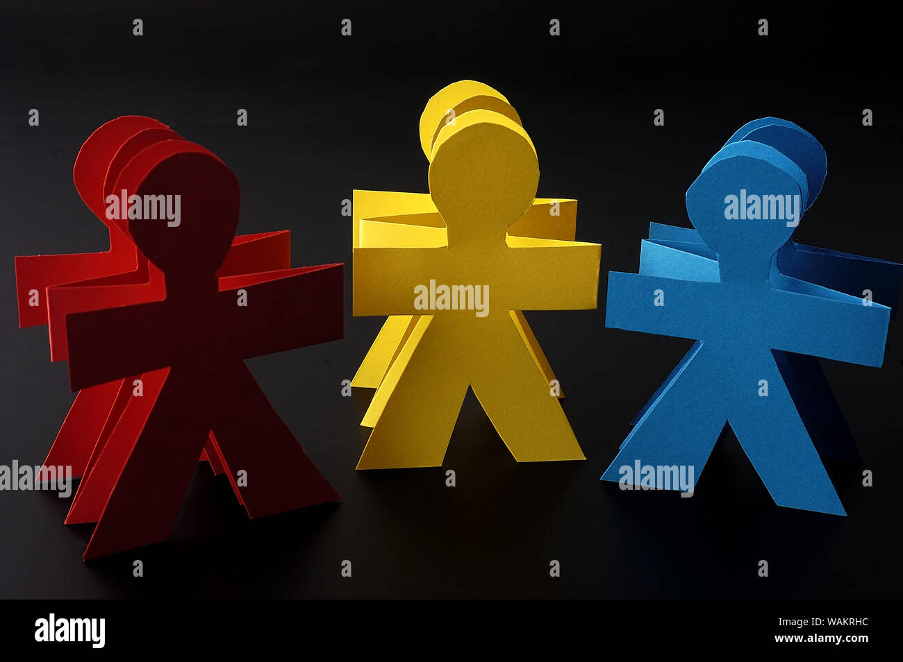 Red yellow and blue paper men isolated on black background Stock Photo ...