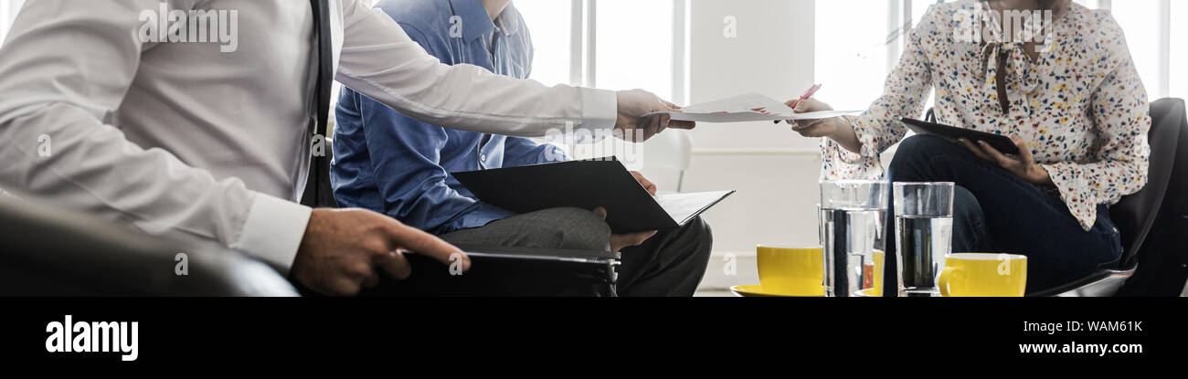 Wide view image of three business partners in a meeting exchanging ...