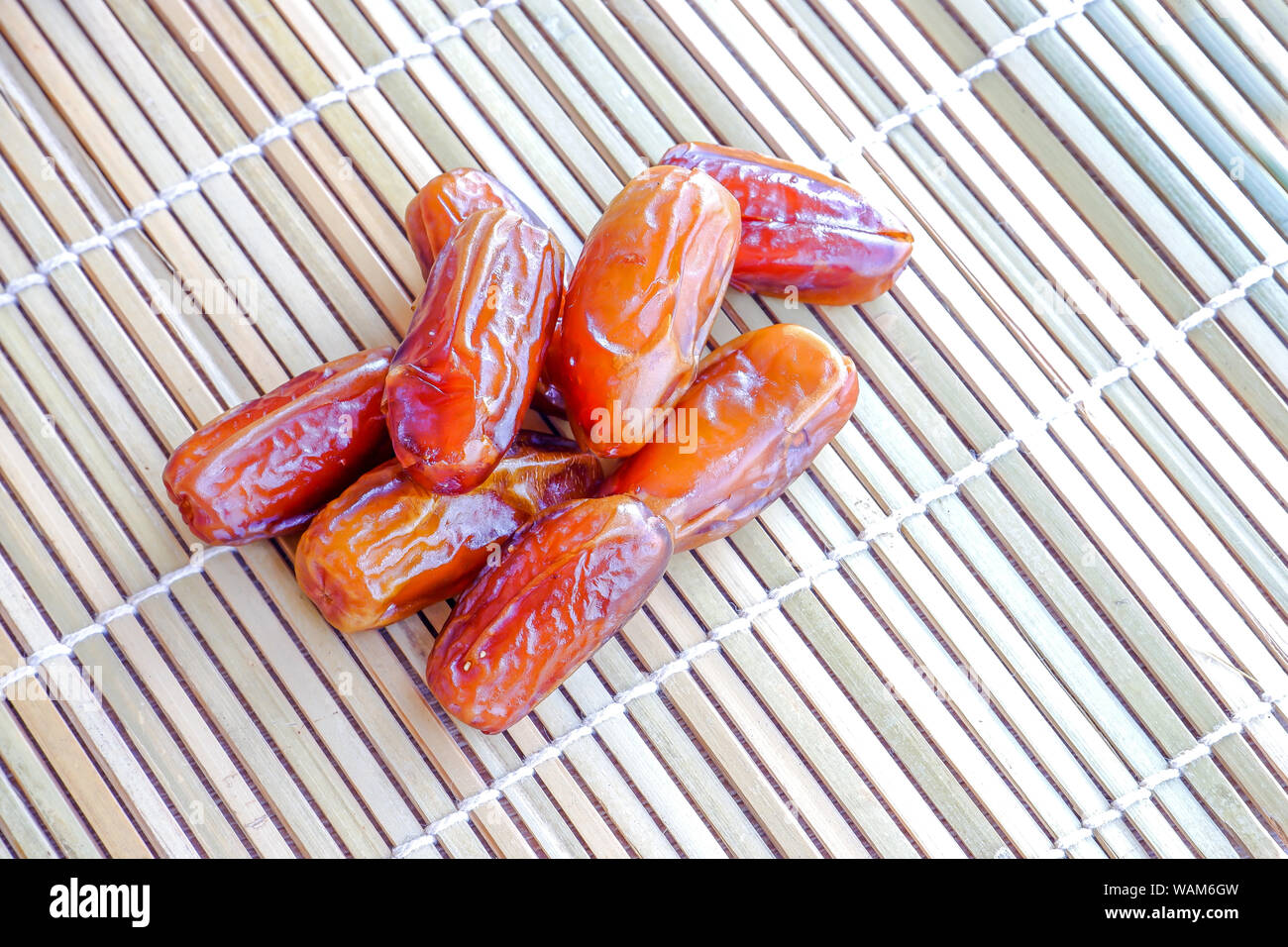 Dried fruits of date palm on bamboo mat background, Phoenix dactylifera ...
