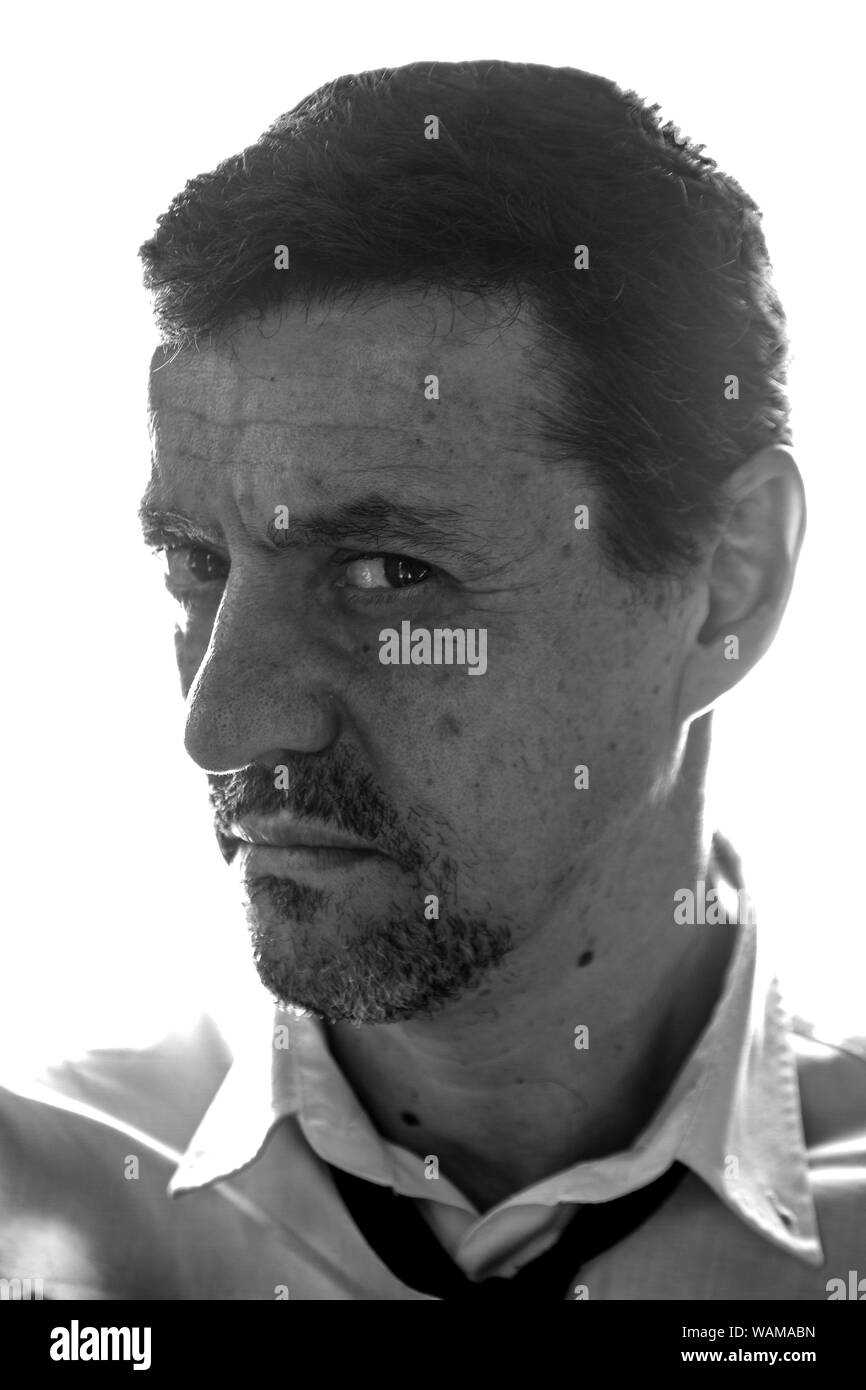 Serious man looking menacingly backlit Stock Photo - Alamy