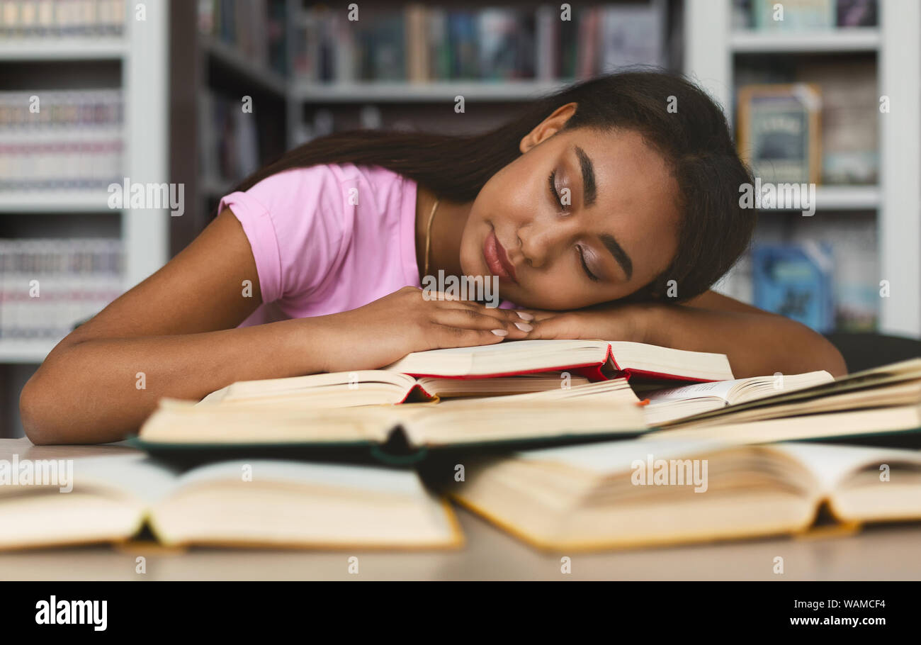 Tired girl napping on books stack in library Stock Photo - Alamy