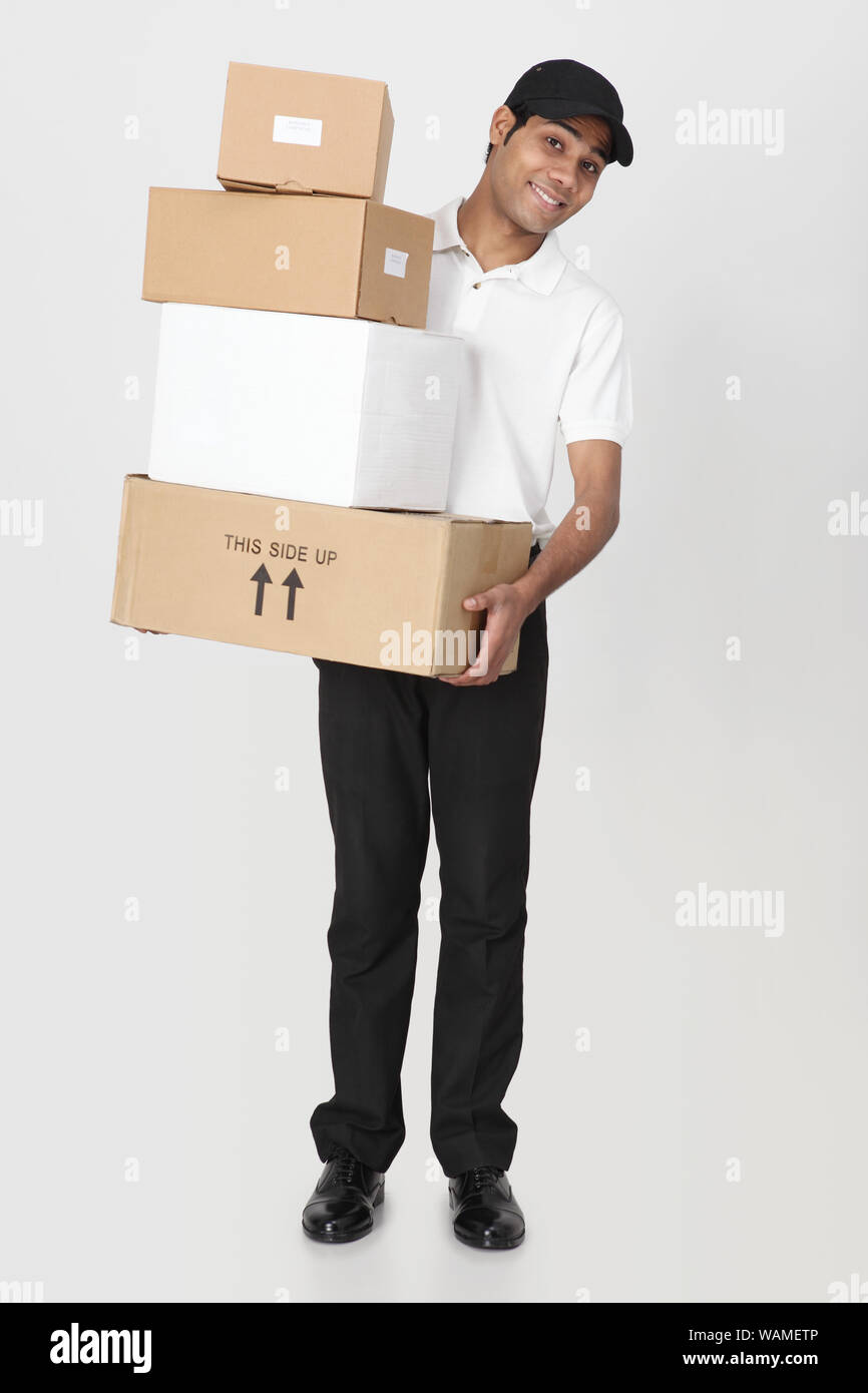 Delivery man carrying stack of parcels and smiling Stock Photo - Alamy