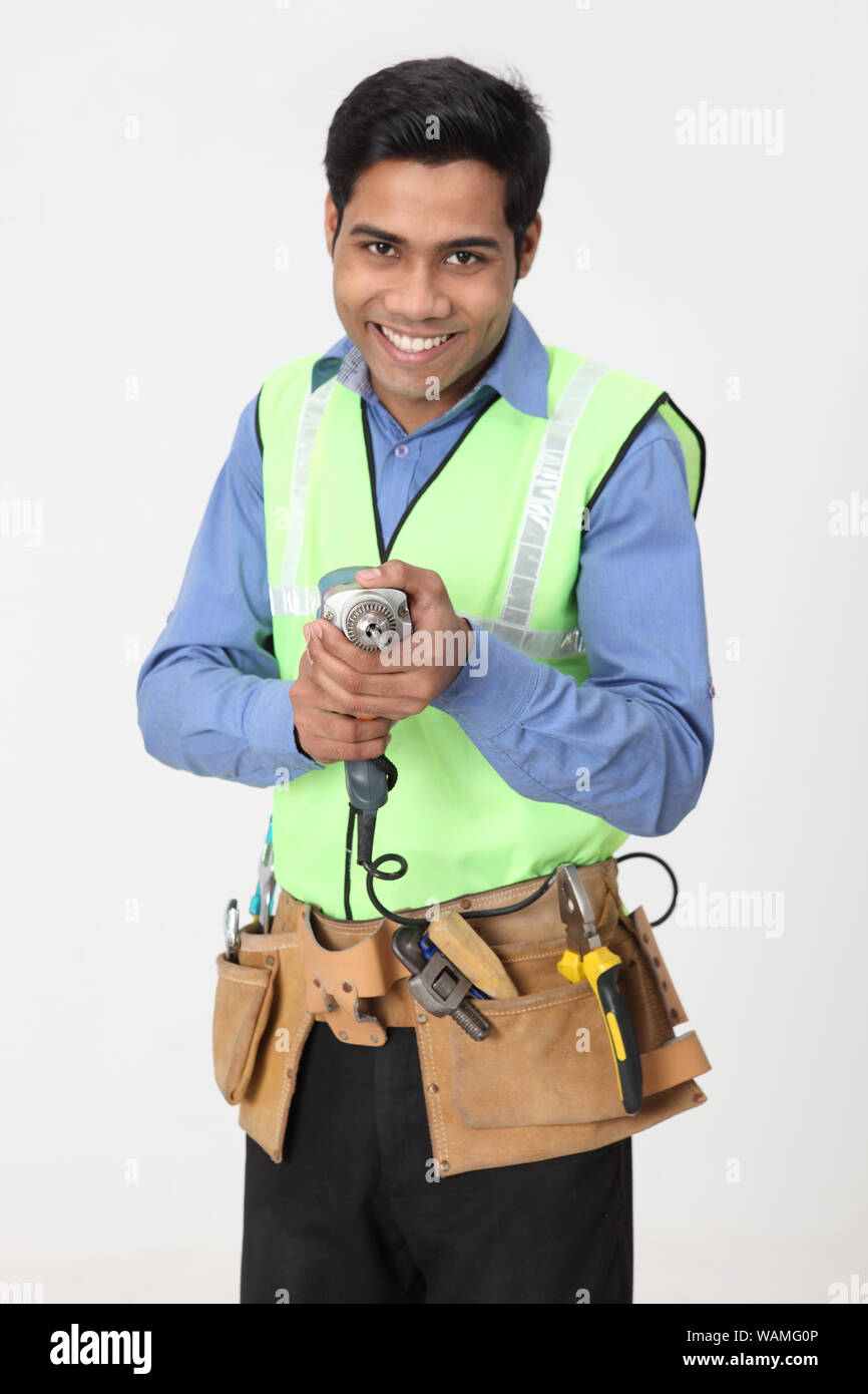 Electrician standing with drill and smiling Stock Photo - Alamy