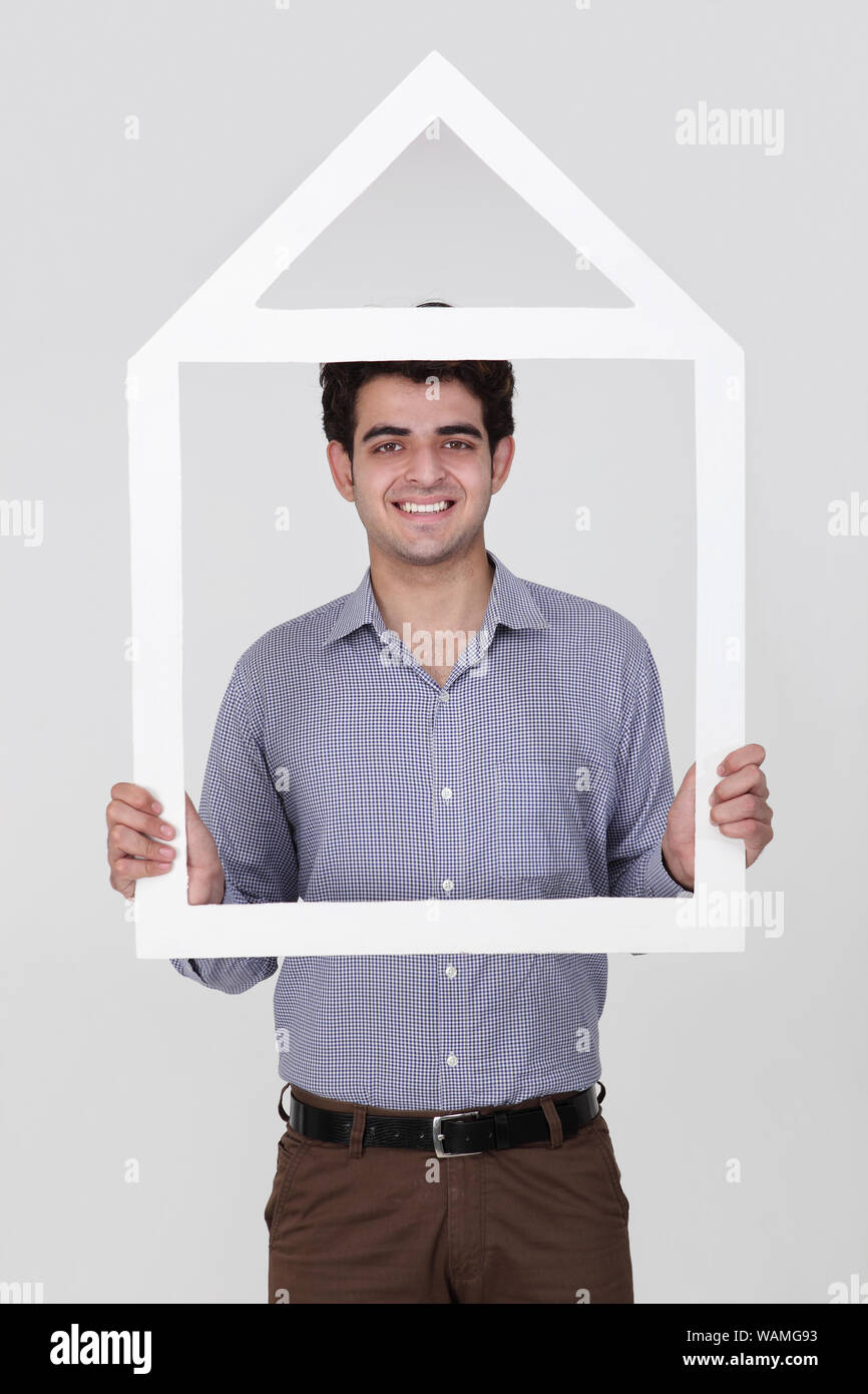 Young man holding a dream home shape frame Stock Photo - Alamy