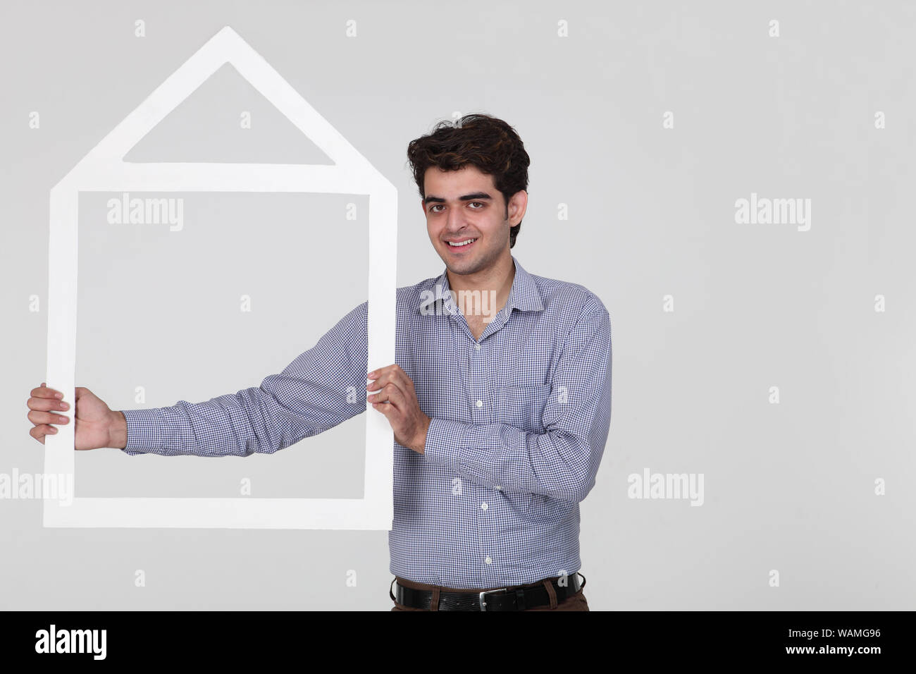 Young man holding a dream home shape frame Stock Photo - Alamy