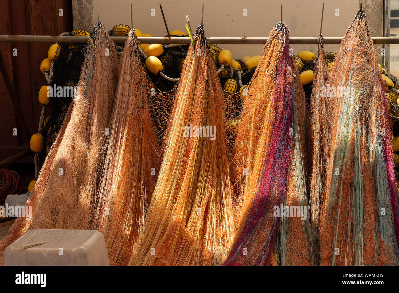 colorful fishing nets hanging on hooks for repair Stock Photo - Alamy