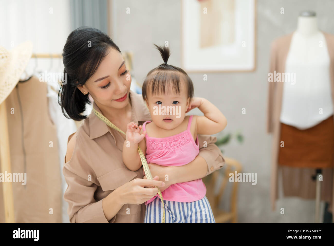 Working together. Young beautiful designer standing near her baby girl ...