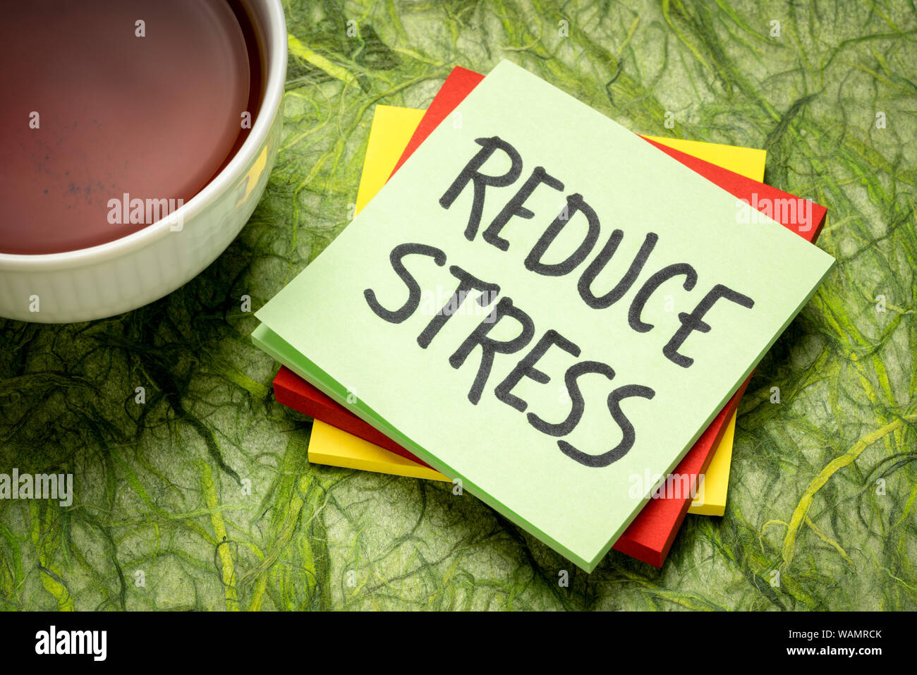 reduce stress - handwriting on a reminder note with a cup of tea ...