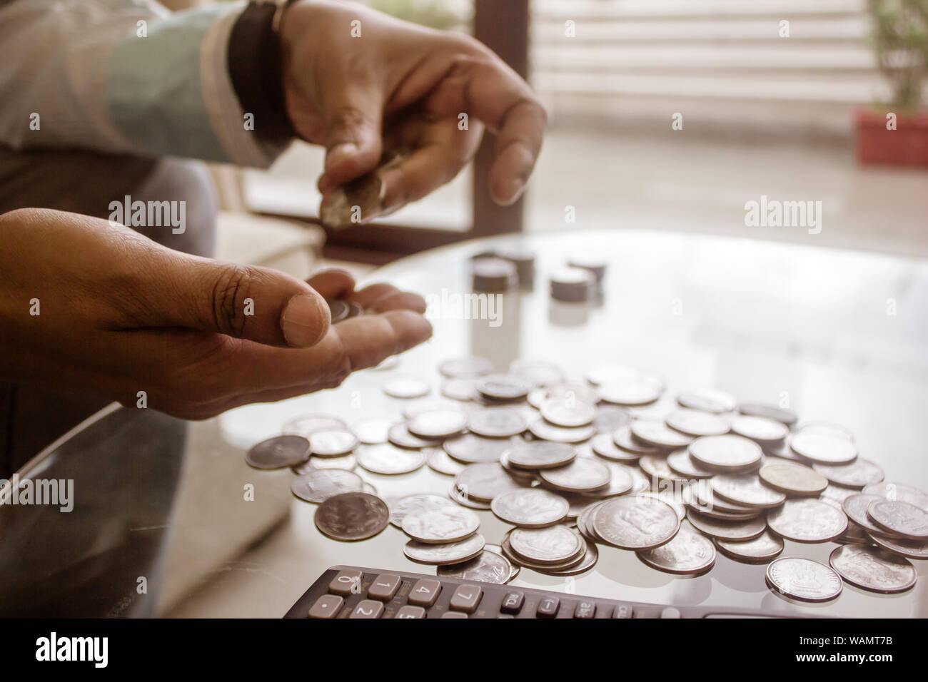Cropped Image Of Businessman counting coins Using Calculator at Desk In ...