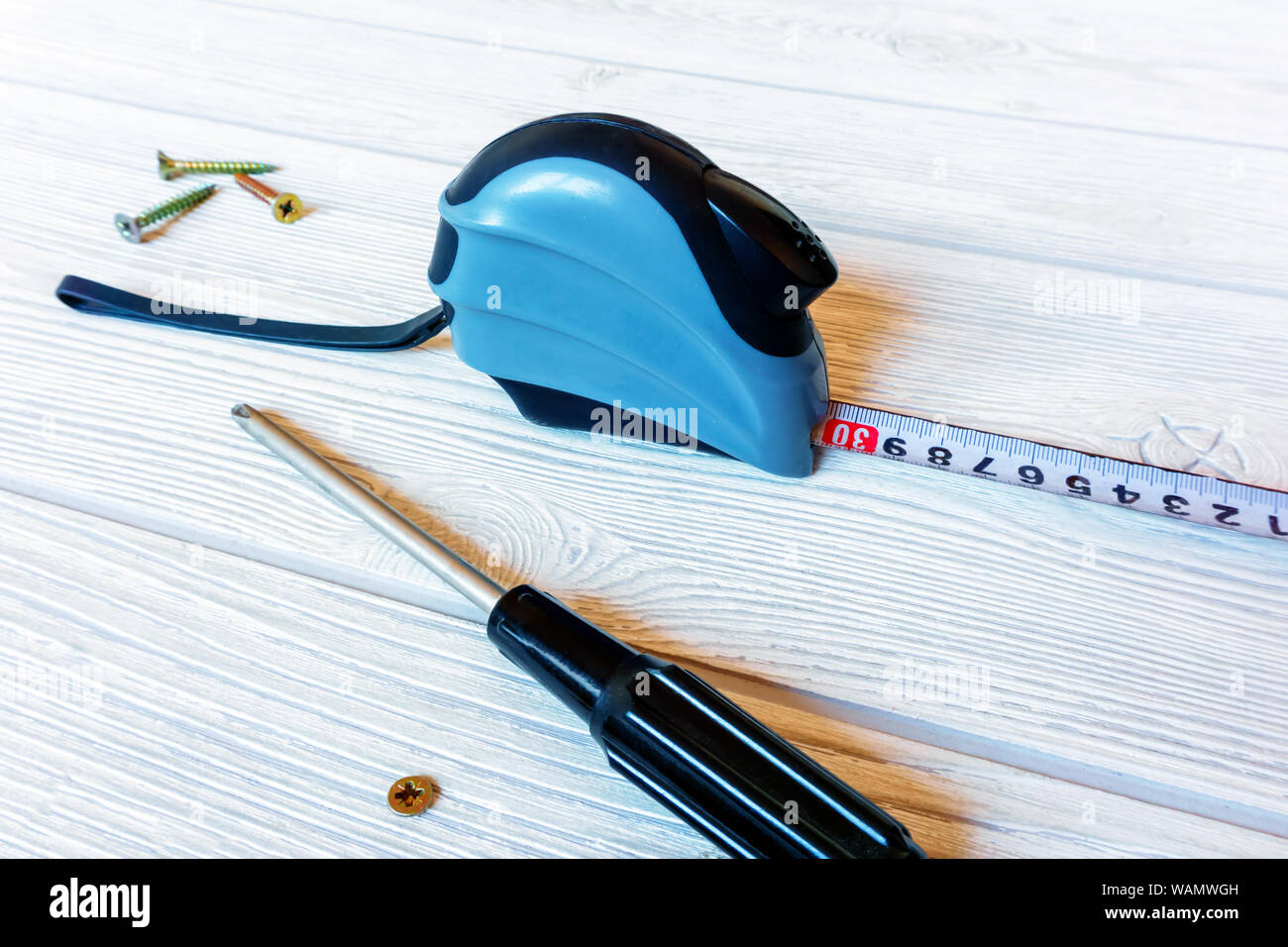 metric self-retracting metal tape measure, screwdriver and screws on a ...