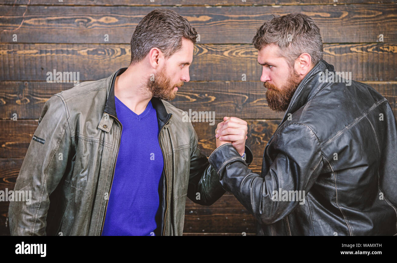 Brutal bearded men wear leather jackets shaking hands. Strong handshake ...