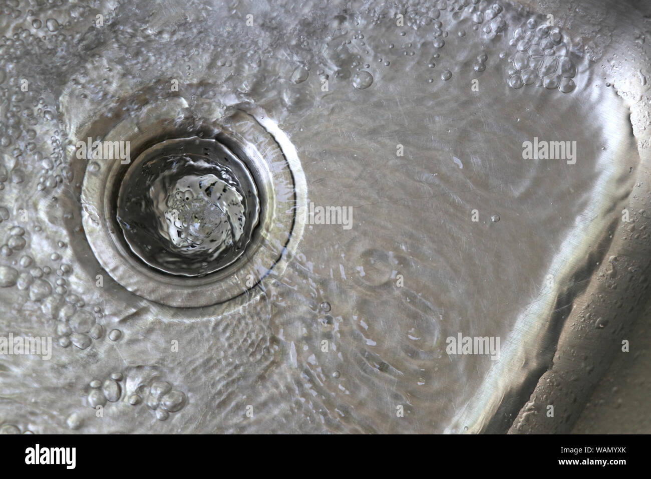 The water in the sink is flowing into the drain. Stainless steel water ...