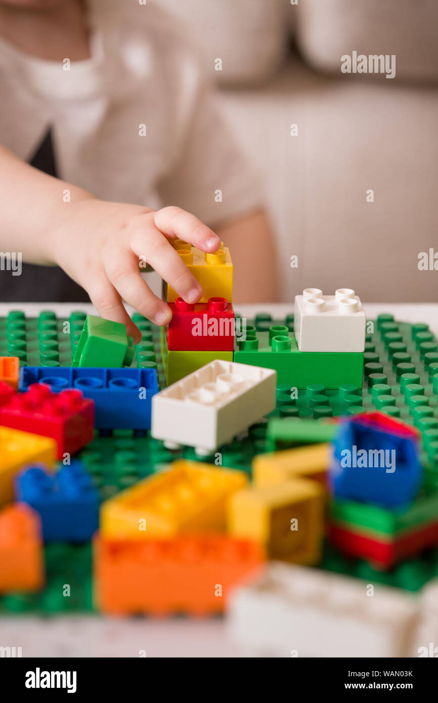 Close up of child's hands playing with colorful plastic bricks at the ...