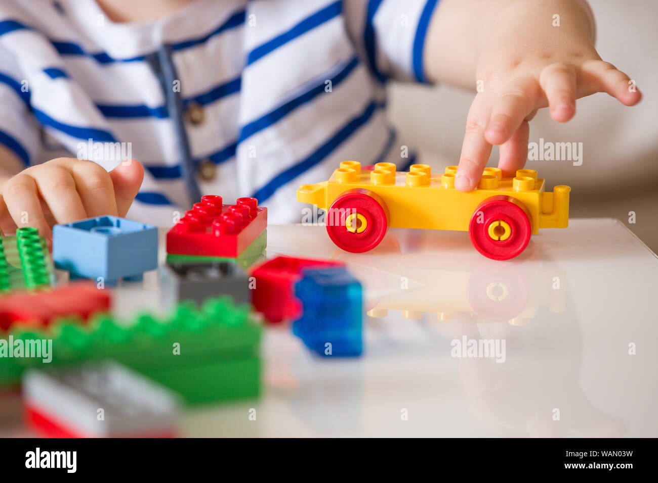 Close up of child's hands playing with colorful plastic bricks at the ...