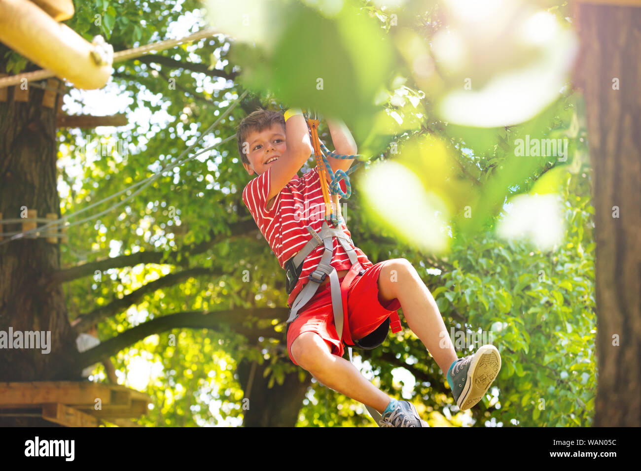 Boy slide down zip line at adventure summer park Stock Photo - Alamy