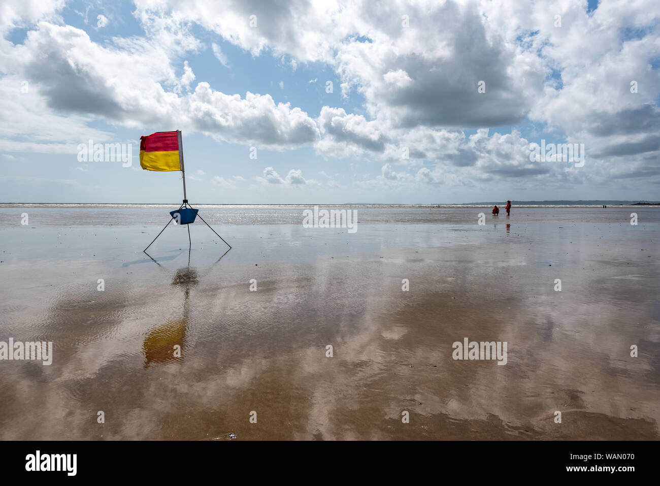 A red and yellow life saving flag against a cloudy blue sky setup by ...
