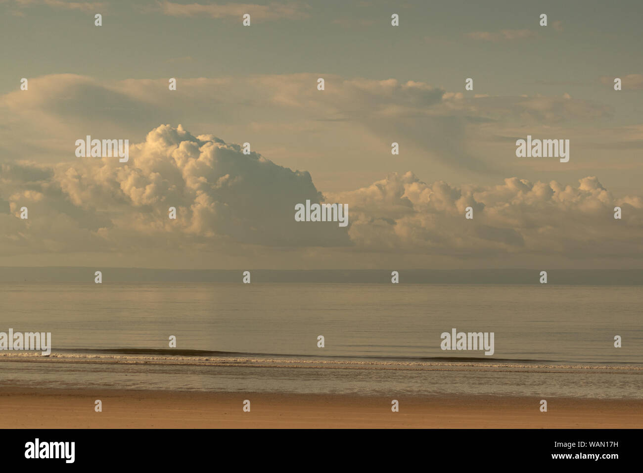 Low Billowing fluffy clouds over a low tide at Swansea beach, wales, U ...