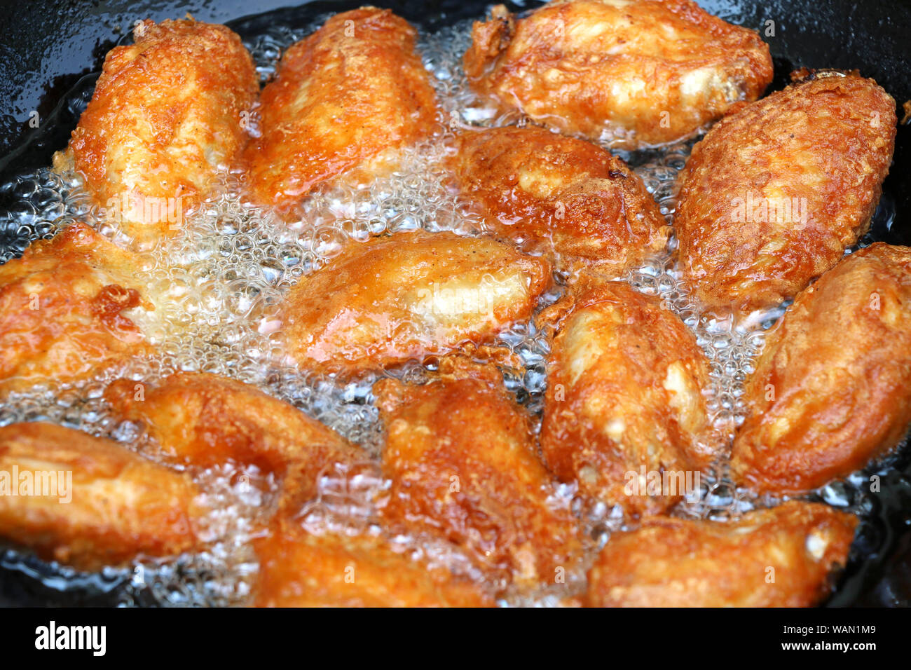 Fried chicken in a pan with hot oil. Golden yellow fried chicken in a ...
