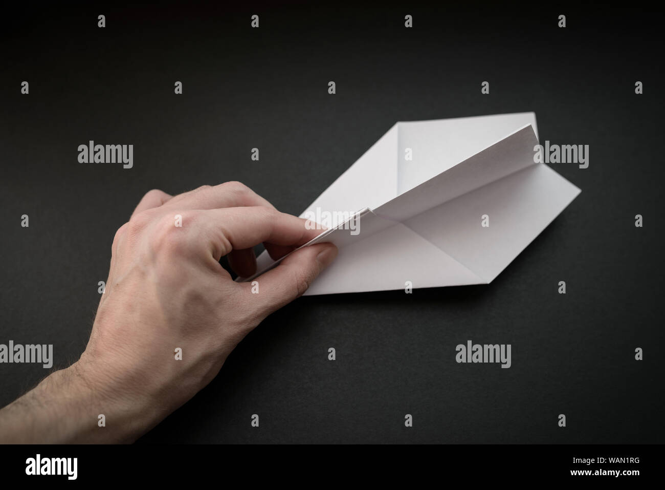 Paper plane in hand on dark background Stock Photo - Alamy