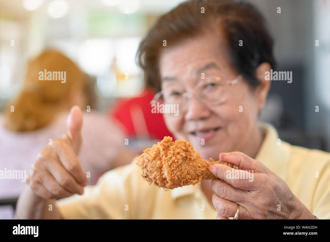 Selective focus of fried chicken, Asian elderly women are eating fried ...