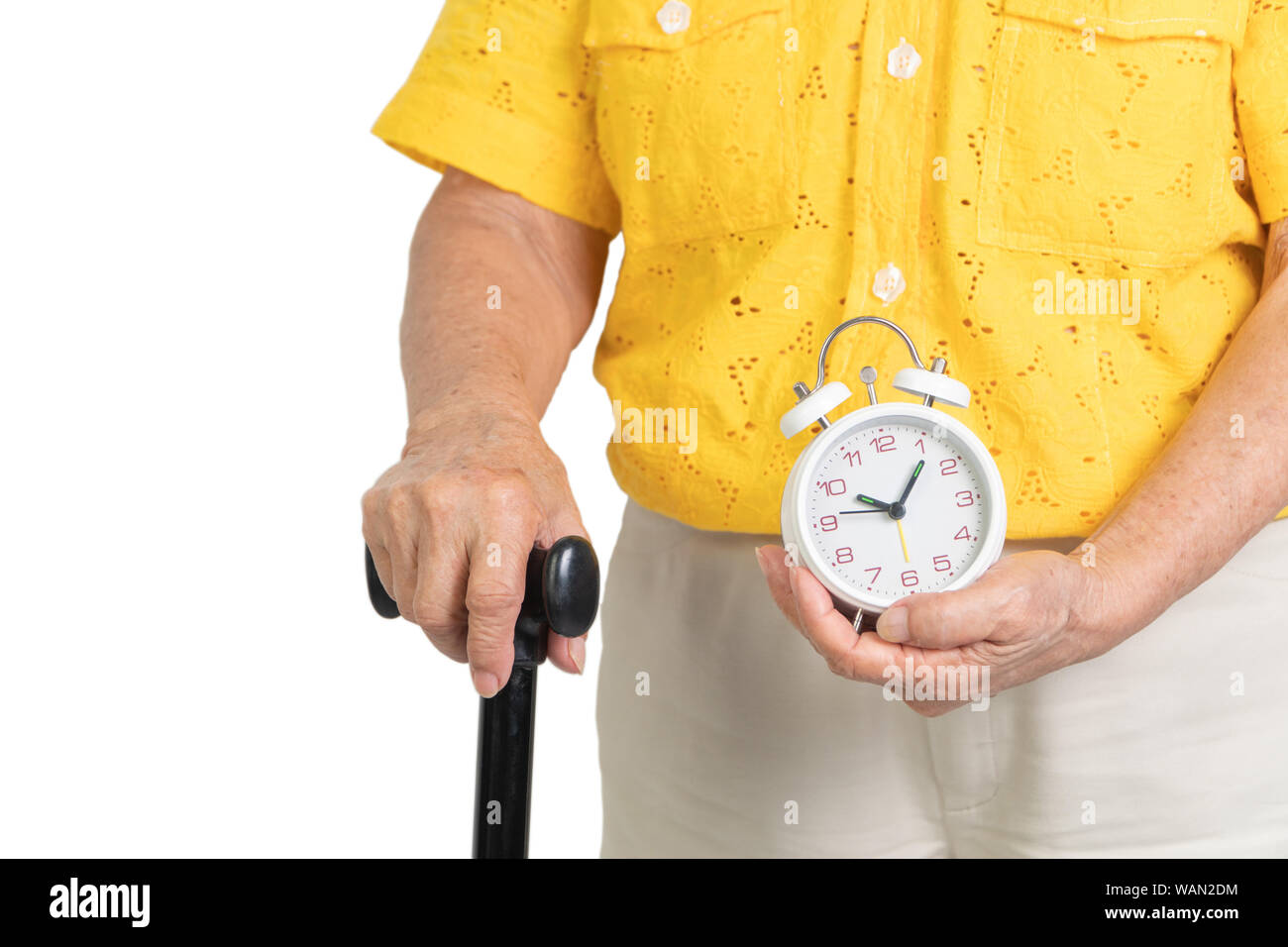 Asian elderly woman holding a white alarm clock and walking stick on ...
