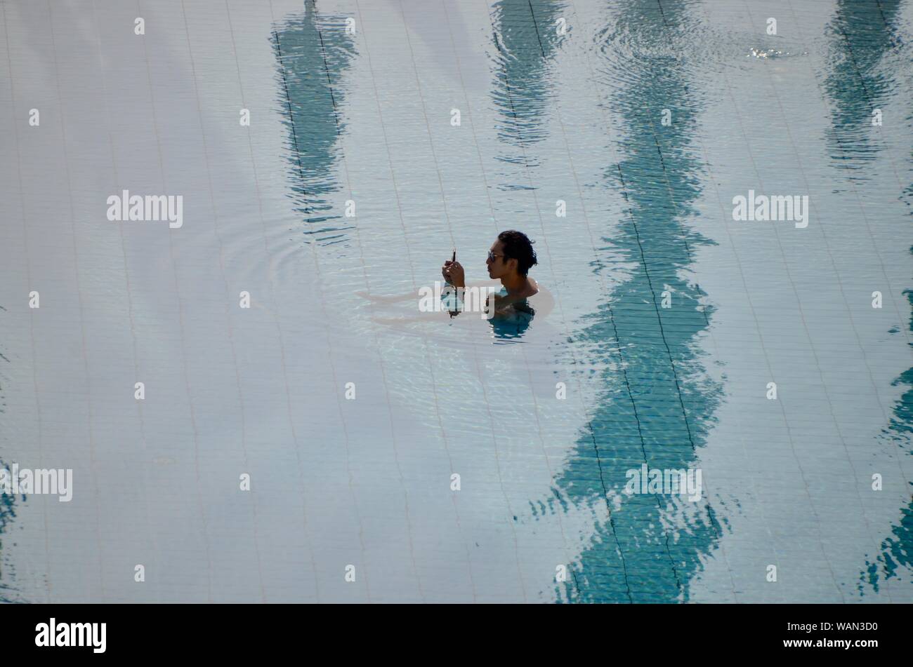 A Japanese Tourist Using His Mobile Phone In A Hilton Swimming Pool