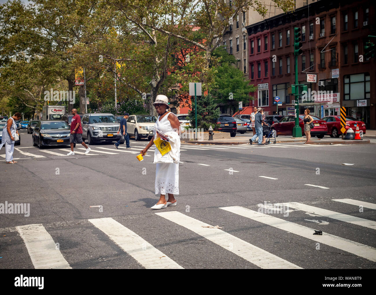 An elderly woman crosses the Lenox Avenue in the New York neighborhood ...
