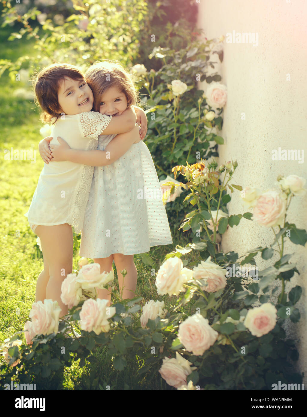 Children smiling at blossoming rose flowers Stock Photo - Alamy