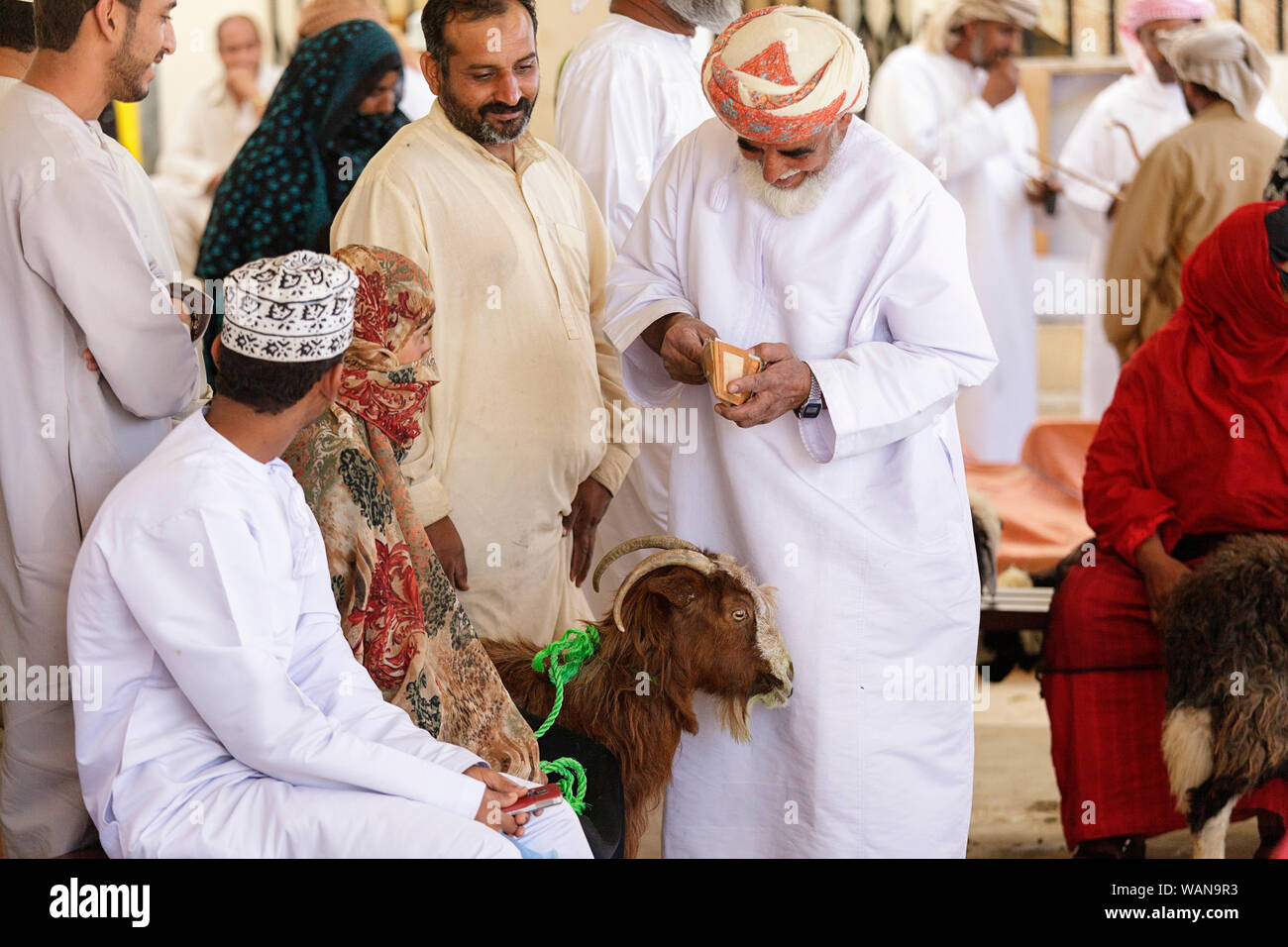Men and women in traditional clothes trading a goat Sinaw market, Oman ...