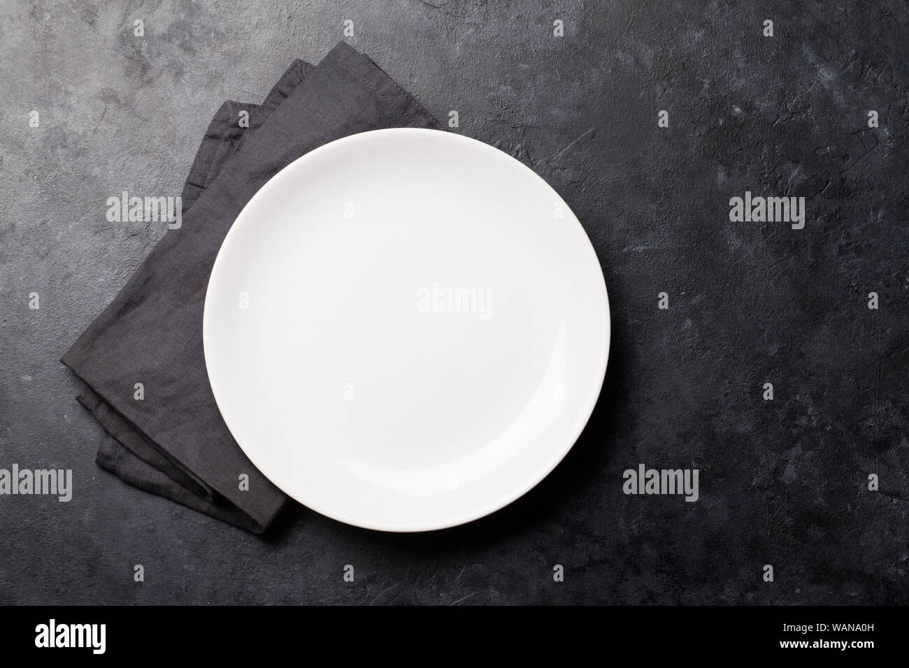 Kitchen table with empty plate and towel. Cooking stone backdrop. Top ...