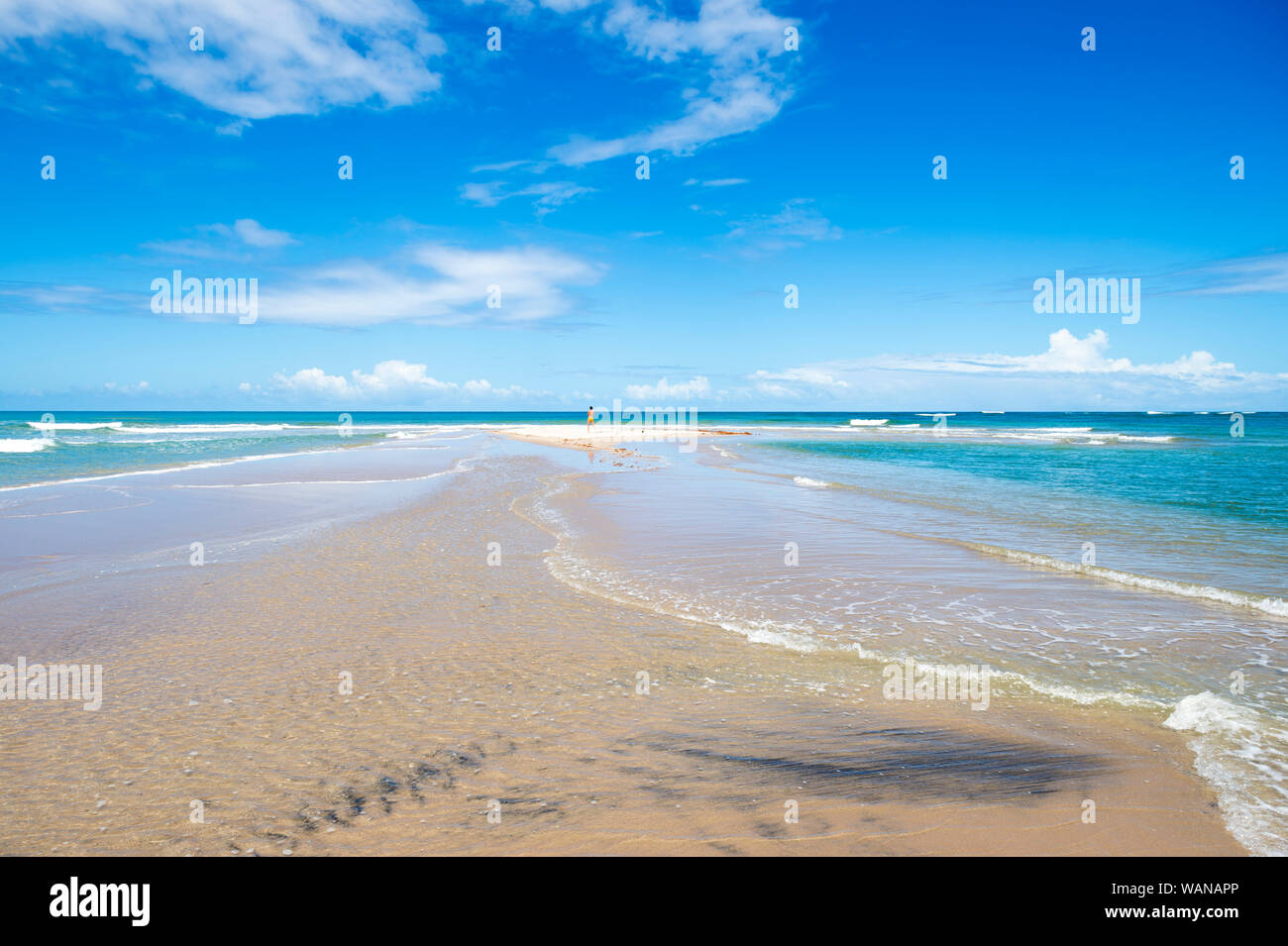Bright scenic view of shallow waves lapping a bar of golden sand ...