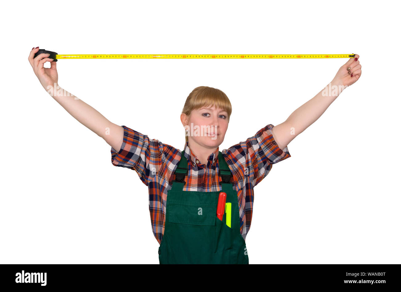 young woman in work overalls holding a tensioned tape measure isolated ...