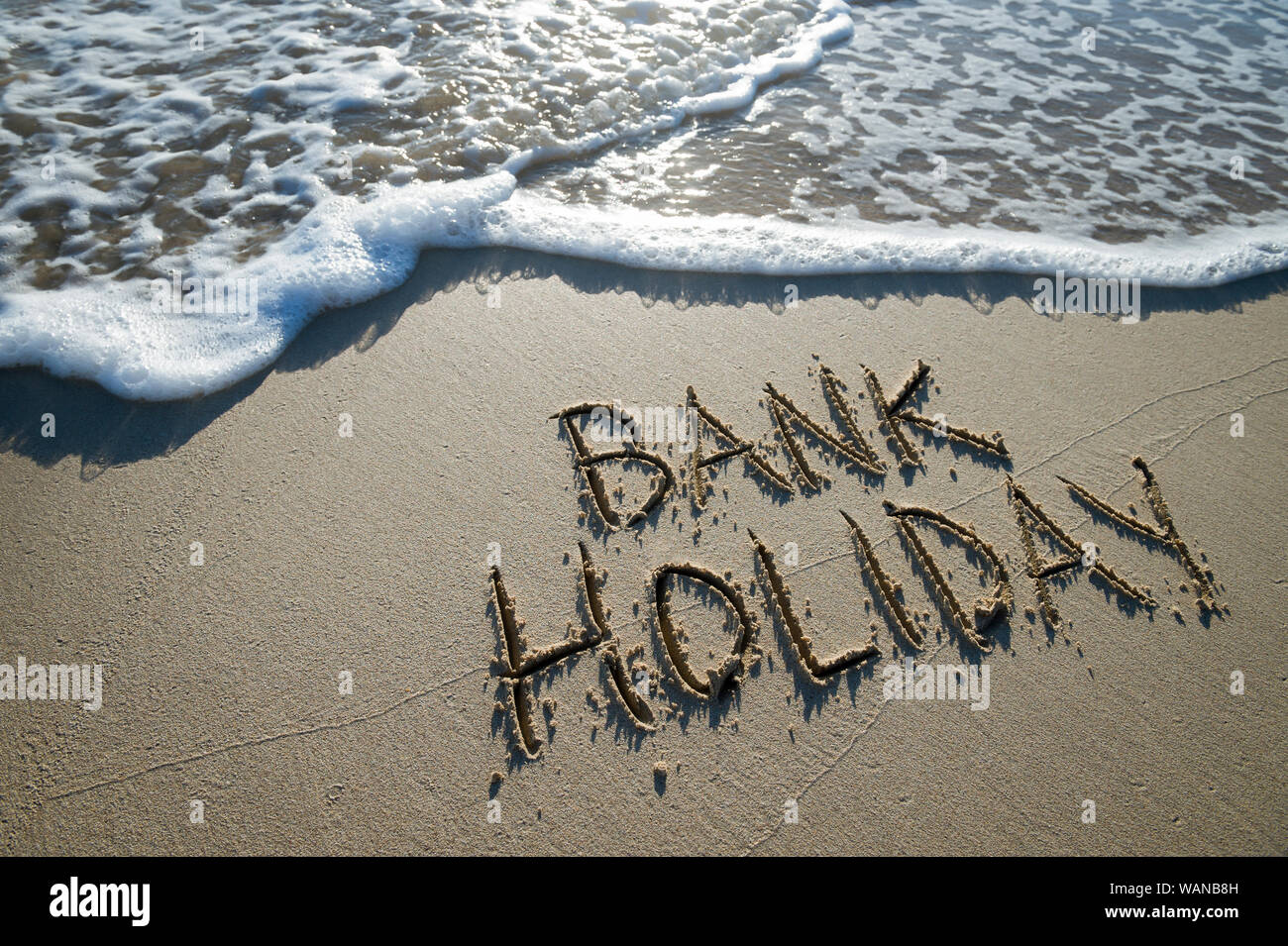 Bank Holiday message handwritten on the smooth sand of an empty beach ...