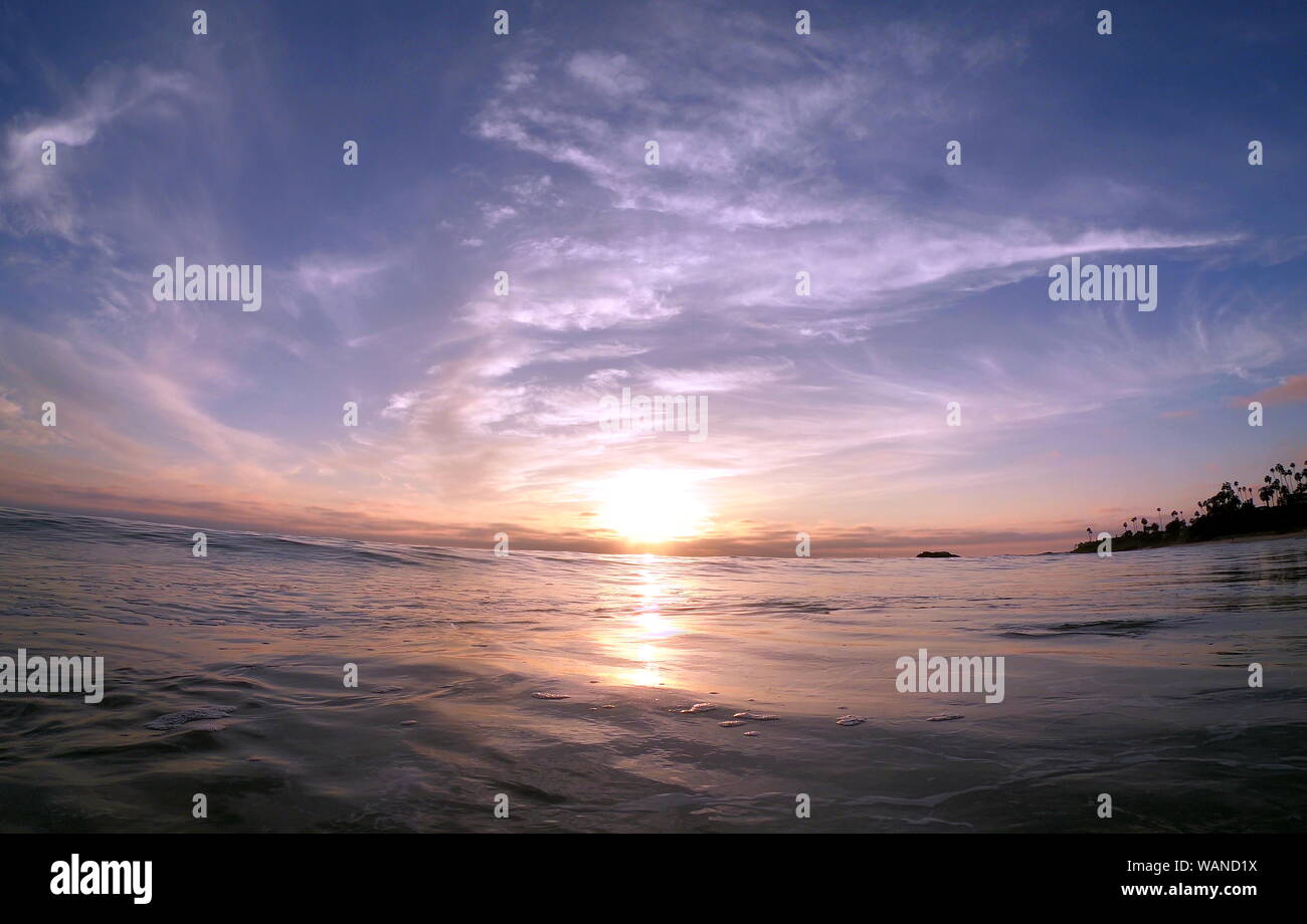 Vibrant sunset reflected by the oily smooth ocean surface POV IN WATER ...