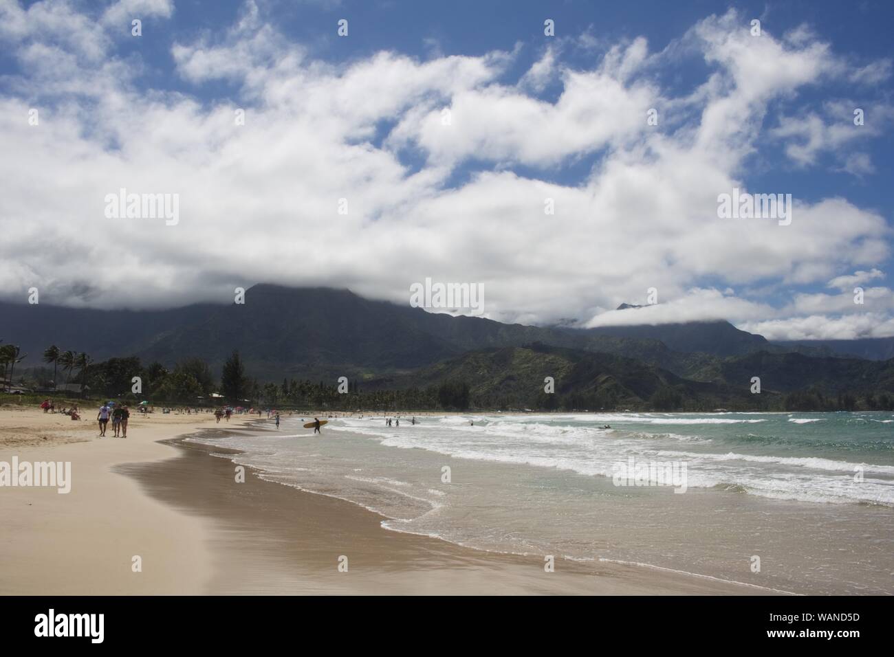 Mountain and Shoreline reflective landscape with surfer at Hanalei Bay ...