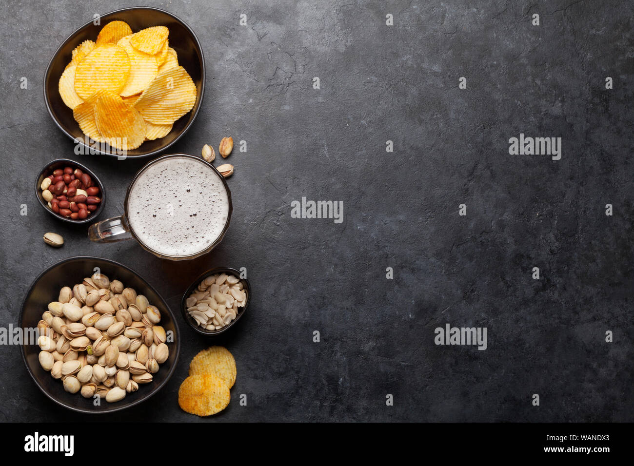Draft beer and snacks on stone background. Nuts and chips. Top view ...