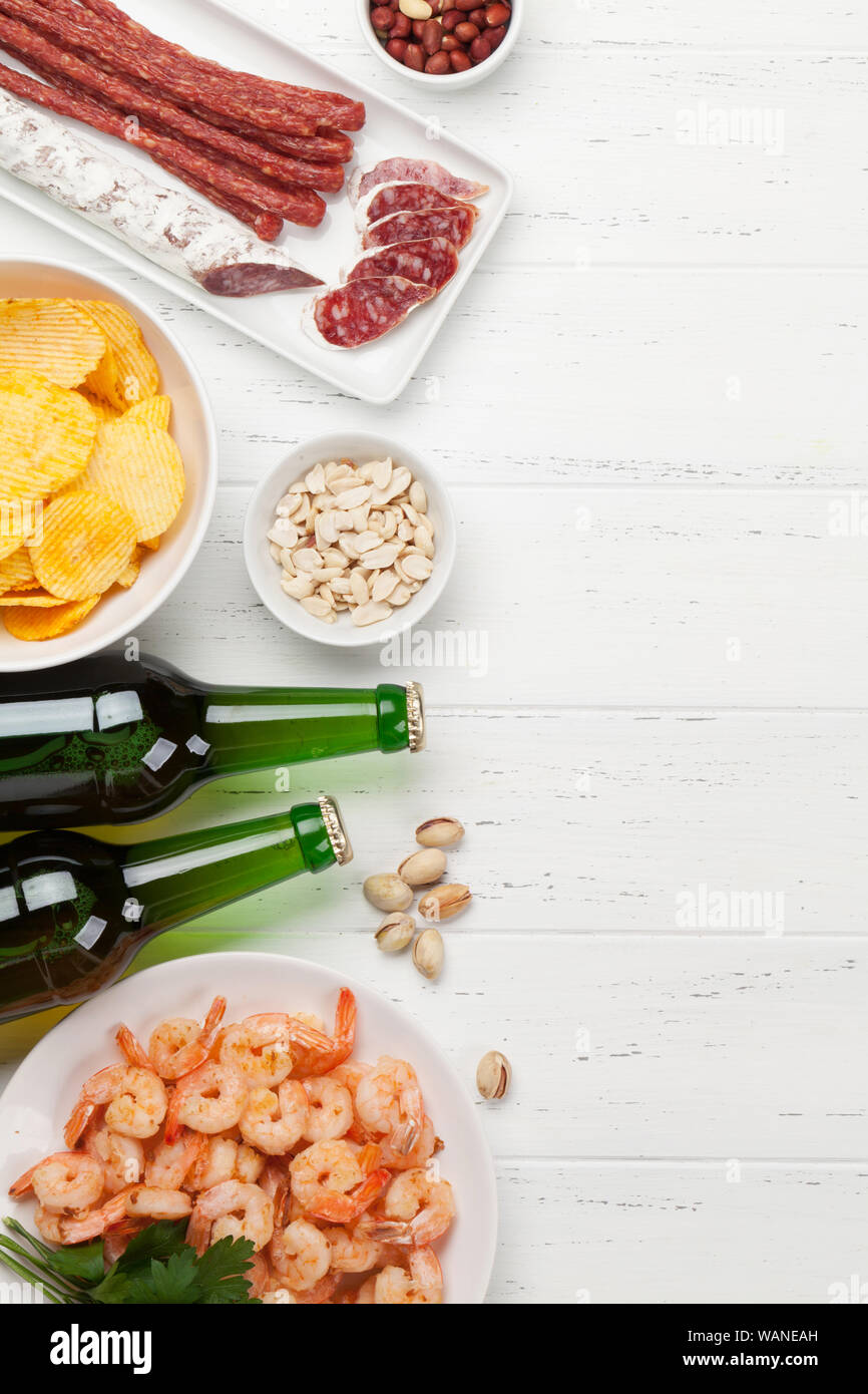 Draft beer and snacks on wooden background. Nuts, chips, sausages and ...