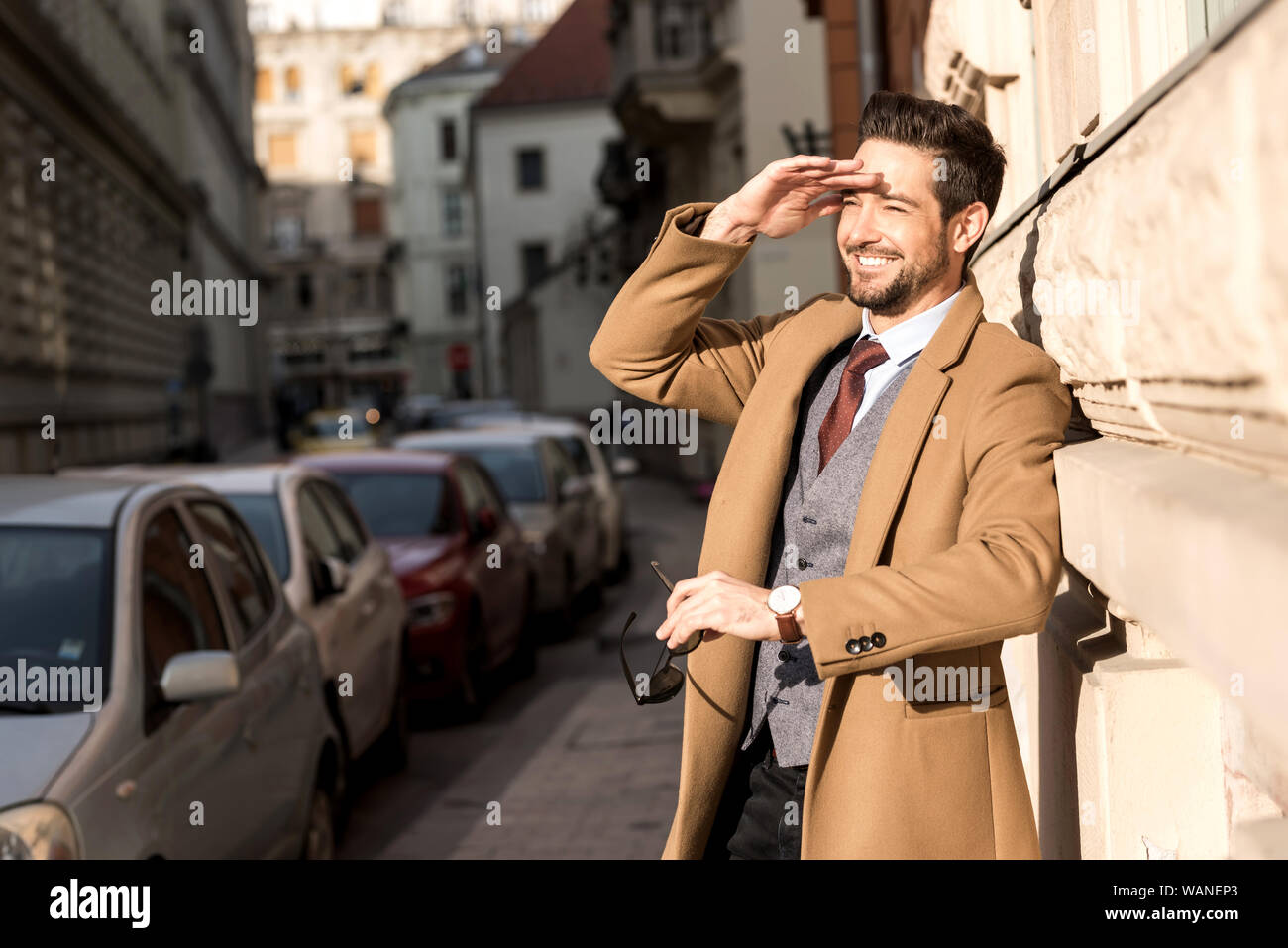 A handsome elegant man walking on the streets and covering his face on ...