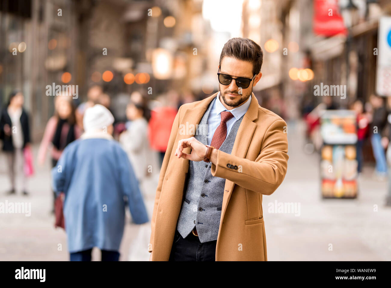 A handsome elegant man walking on the streets and checking the time on ...