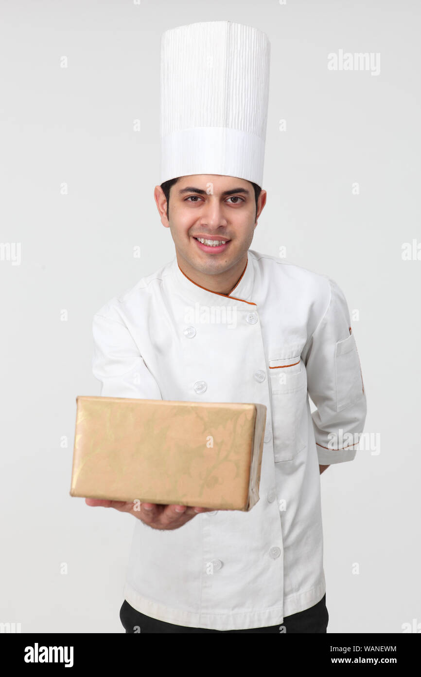 Chef offering a gift box and smiling Stock Photo - Alamy
