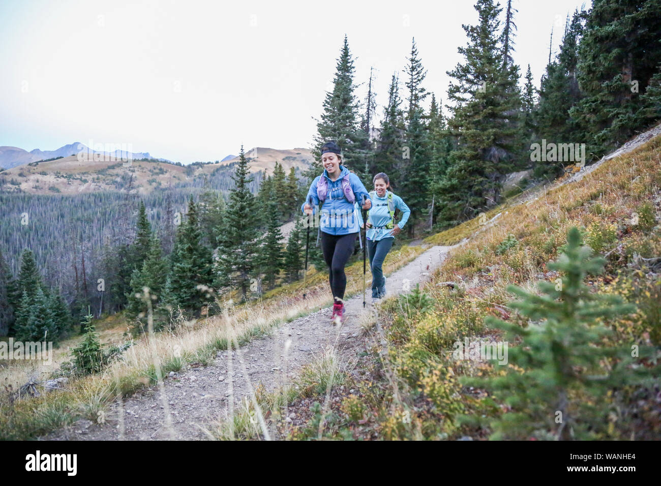 Two young women trail runners enjoy gentle uphill single track trail ...