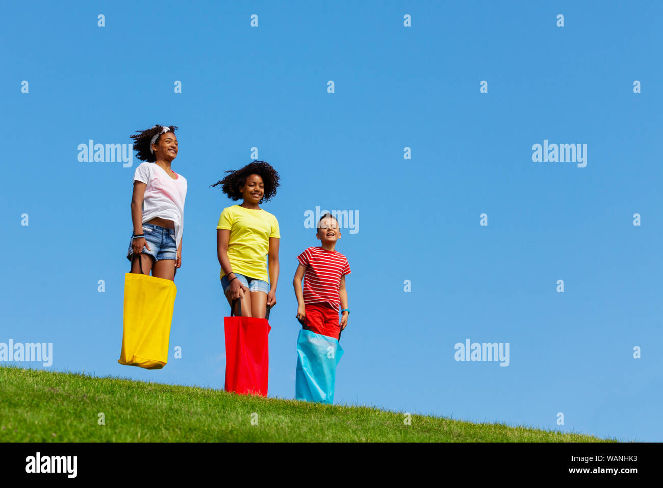Kids play sack race game jumping hoping downhill Stock Photo - Alamy