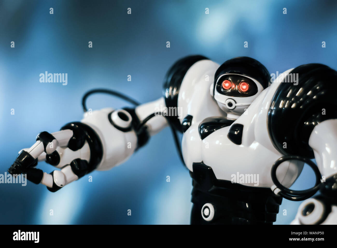 partially blurred toy robot with glowing red eyes on a blue background ...