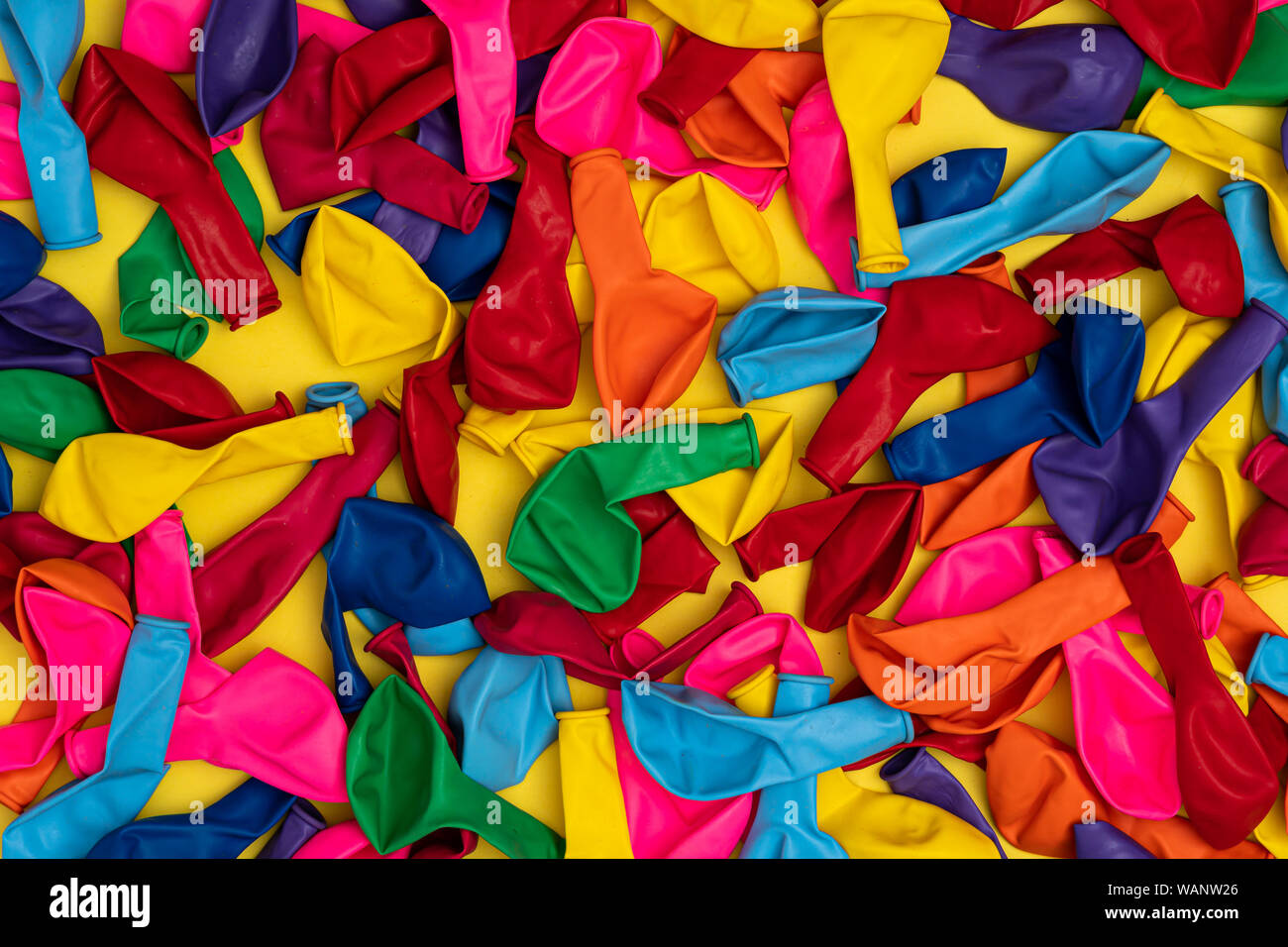 Top view of deflated colorful balloons on yellow background, Colored ...