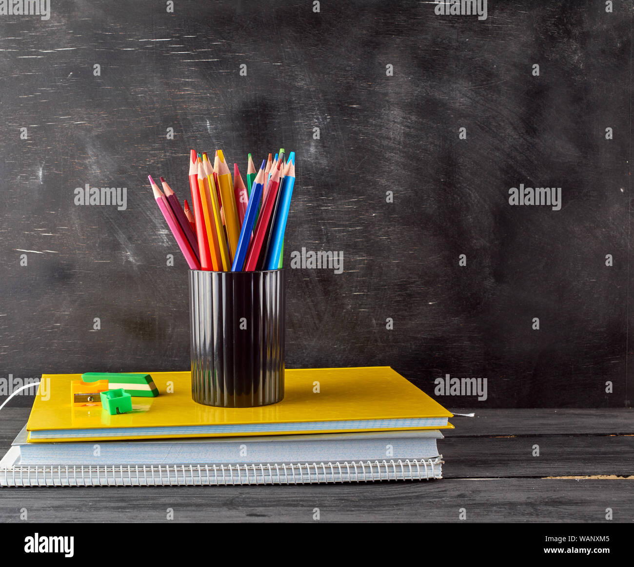 stack of notebooks, black stationery glass with multi-colored wooden ...